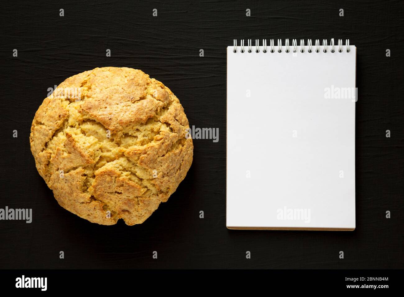 Homemade Irish Soda Bread, blank notepad on a black surface, top view ...