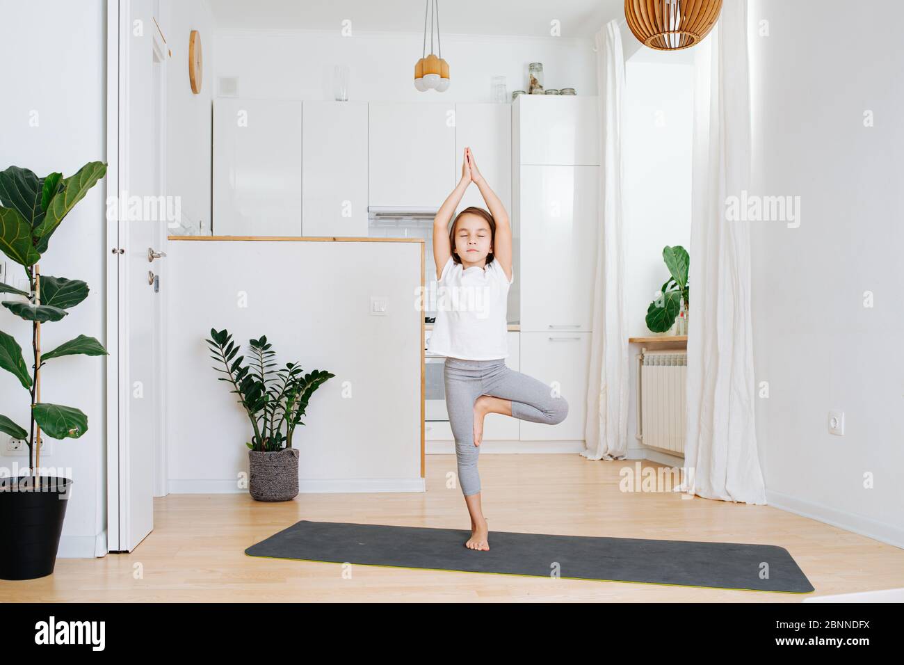 Little kid standing on one leg, meditating with joined hands Stock ...