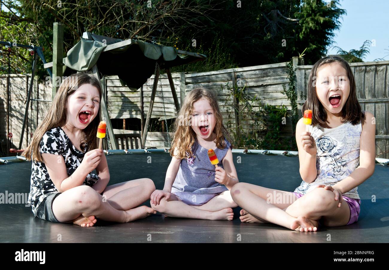 three girls eating popsicles on trampoline in Woking - England Stock ...