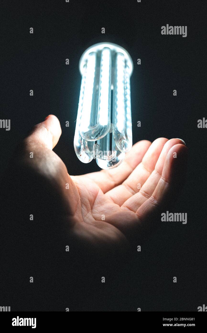 Led light bulb on illuminating a human hand on dark background Stock ...