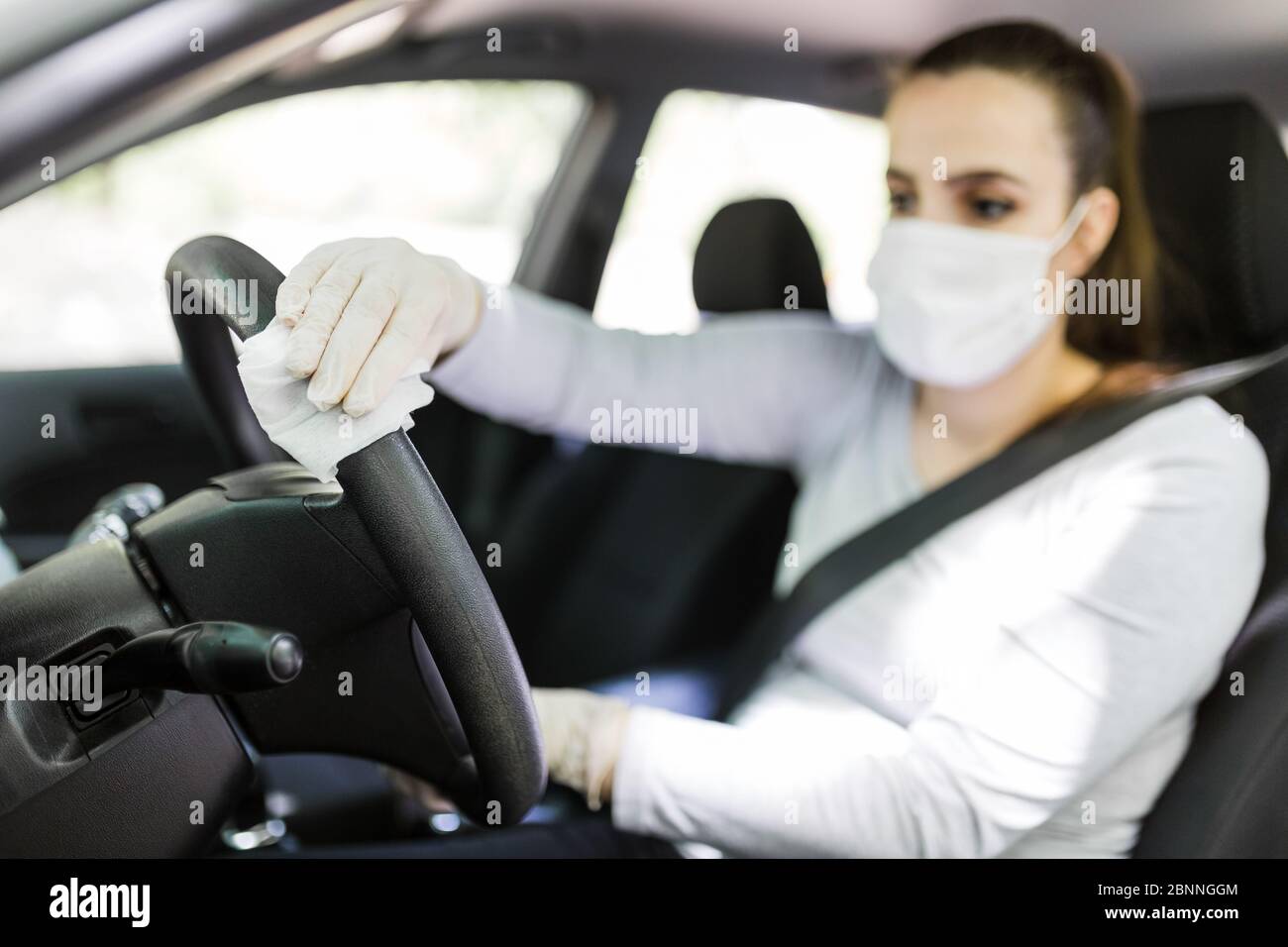 Female driver using wet wipe for disinfecting car steering wheel ...