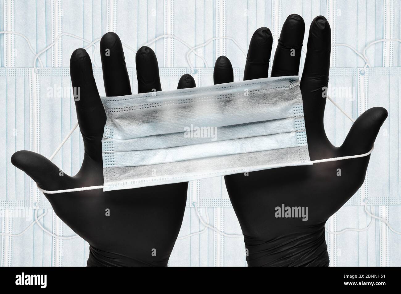 Paramedic holding protective face mask in two black medical glove in ...