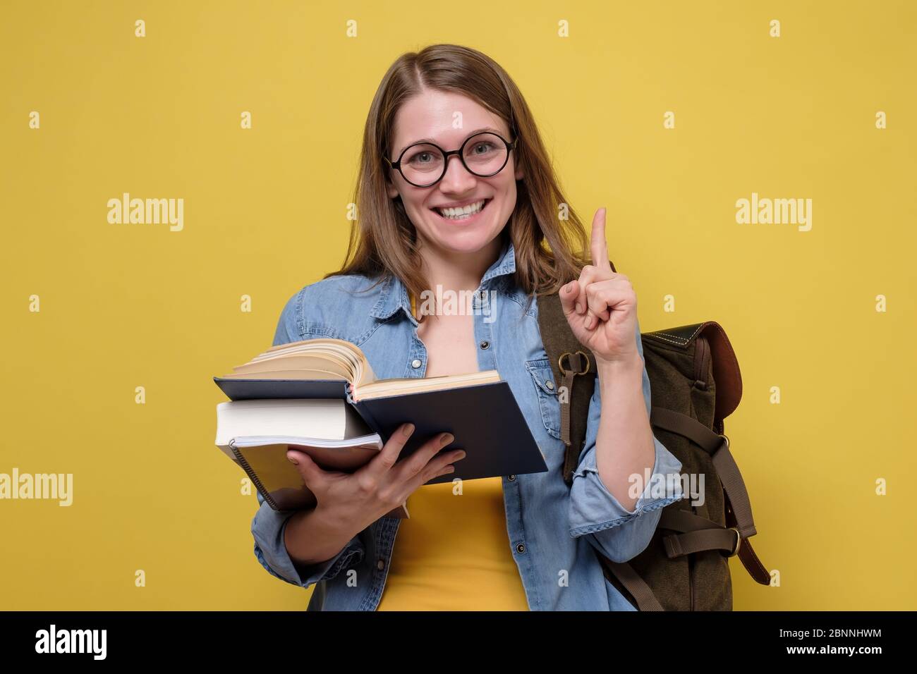 Attractive young female college student carrying a stack of books ...
