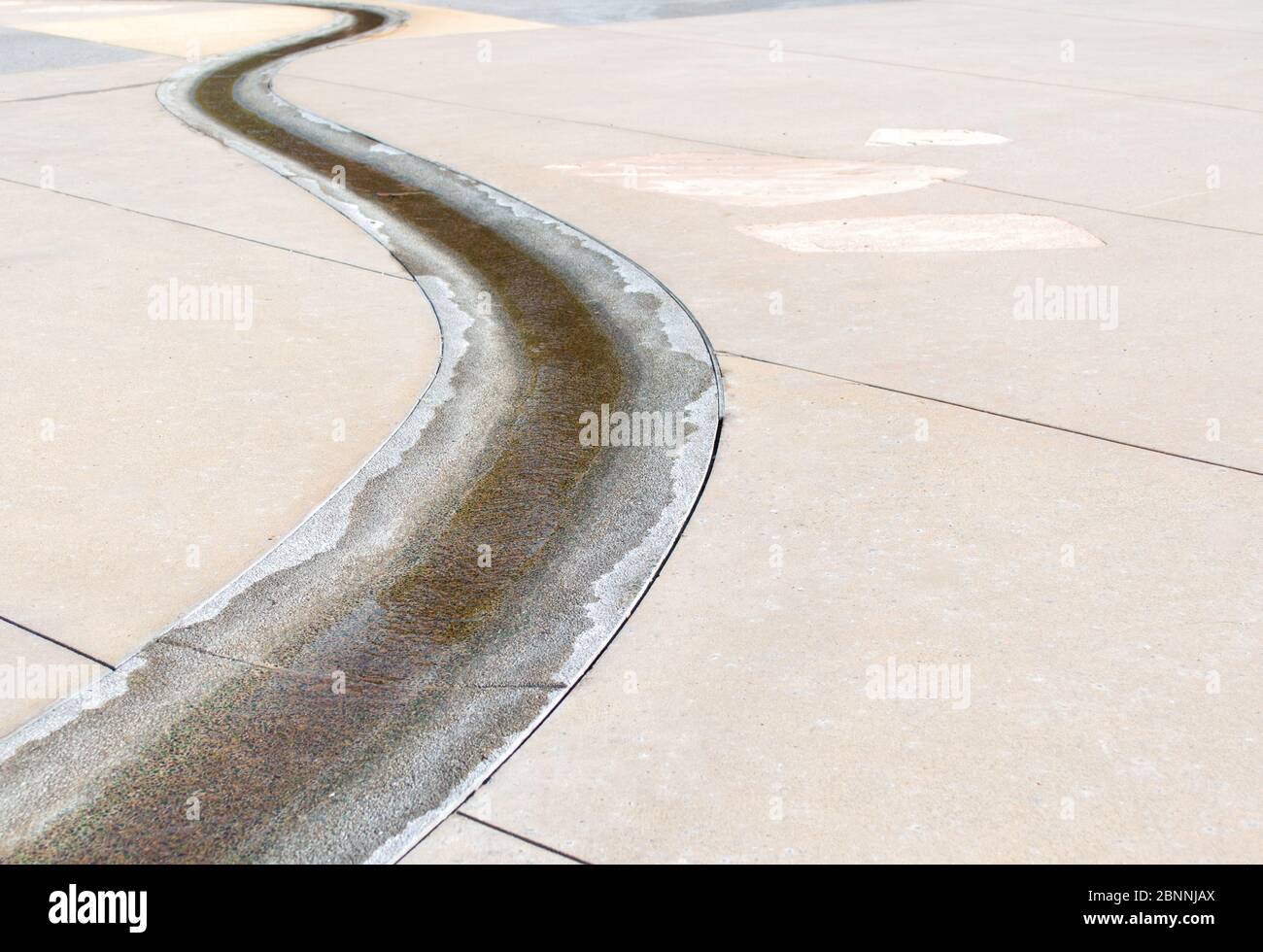 a small cement outdoor waterway meandering through an empty sidewalk ...
