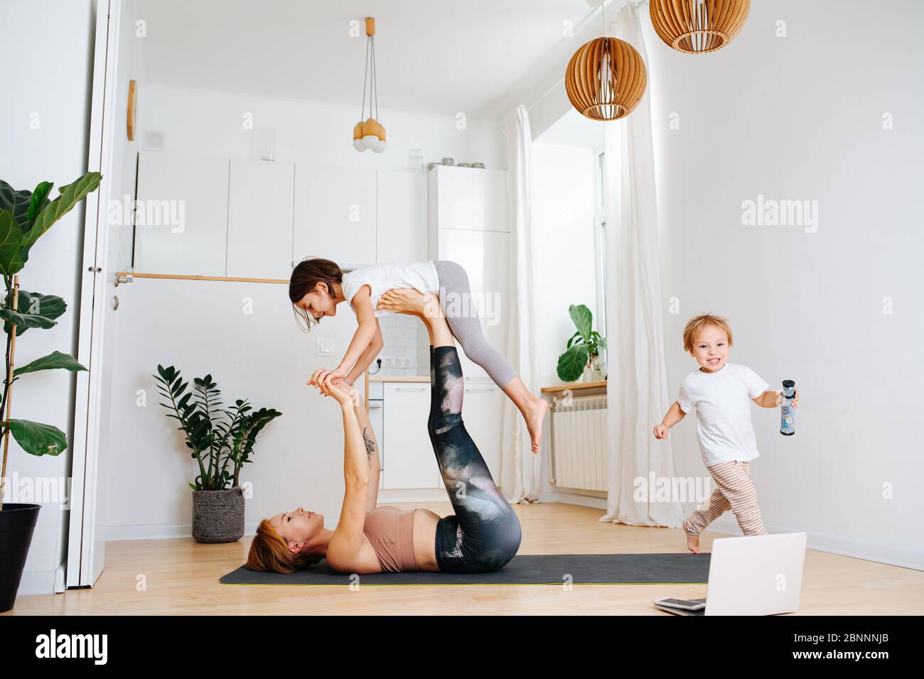 Parent and child doing gymnastic form while little son running around ...