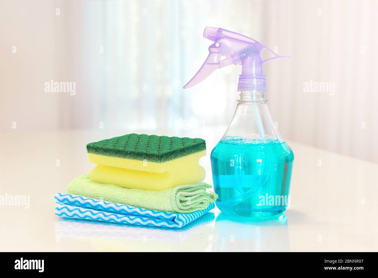 Cleaning products on a table. Light blue spray, sponge and cleaning ...