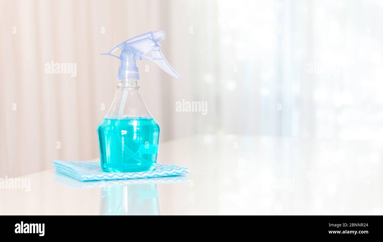 Cleaning product. Spray bottle with light blue liquid on a white table ...
