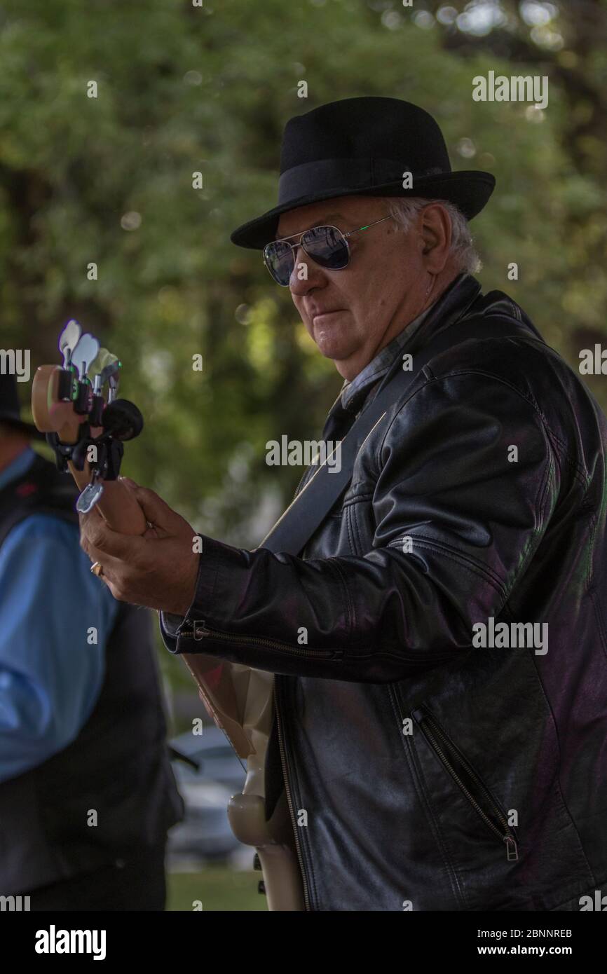 Senior male playing bass guitar in rock band at outdoor rock concert ...