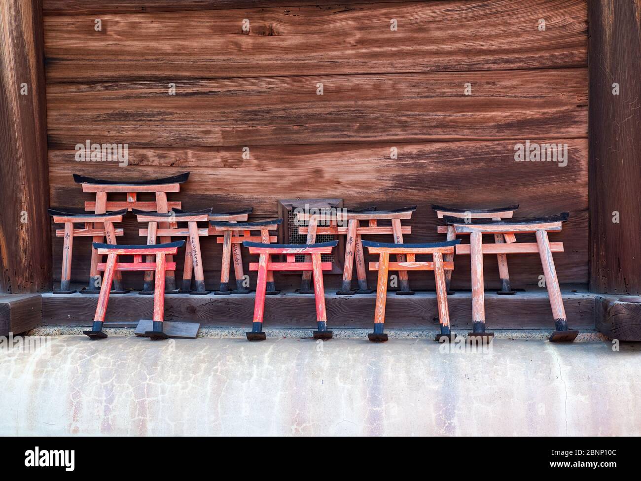 Small wooden orange-red torii gate model with wishes written on them at ...
