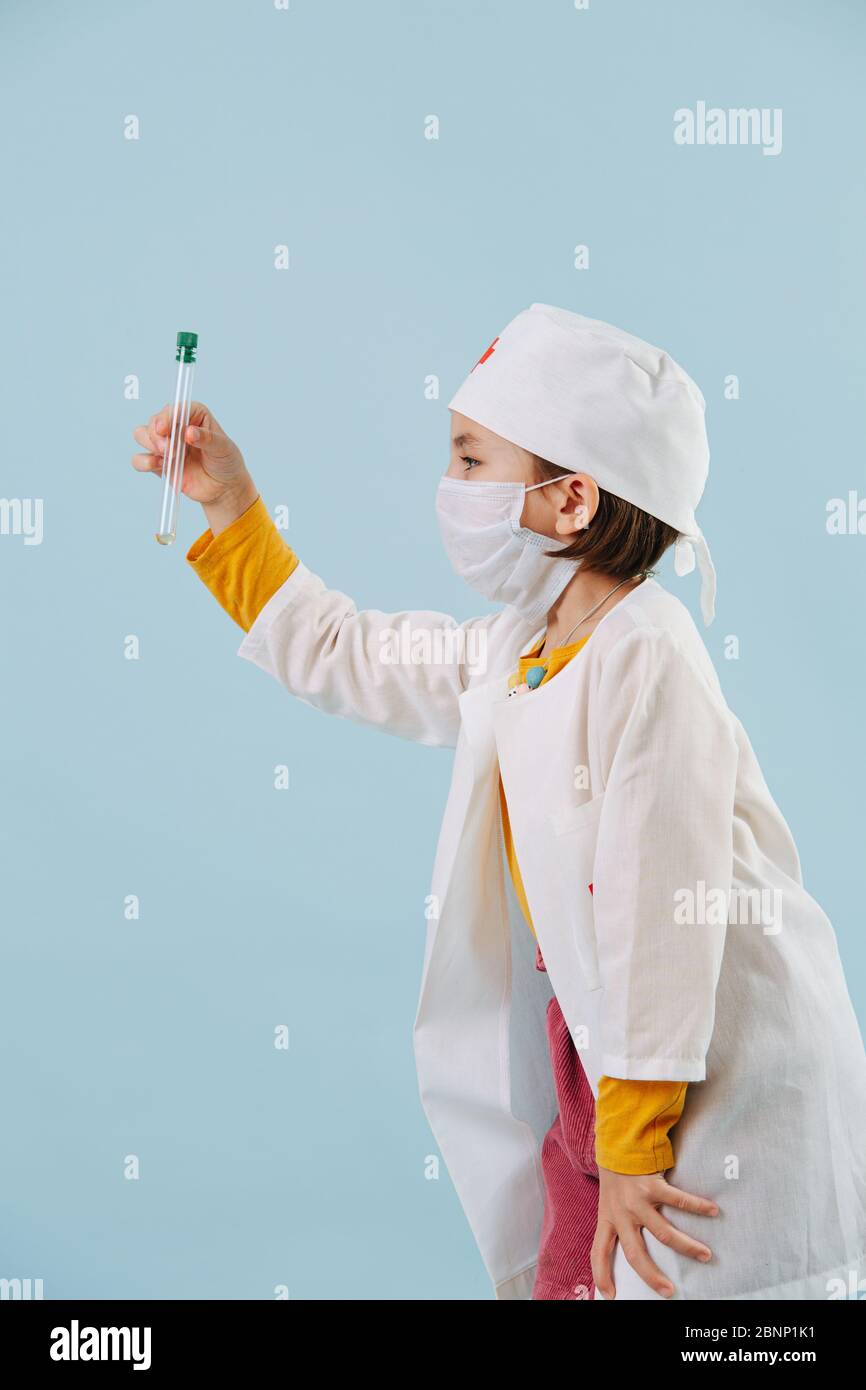 Little girl dressed in lab tester outfit looking at vial, pretending it ...