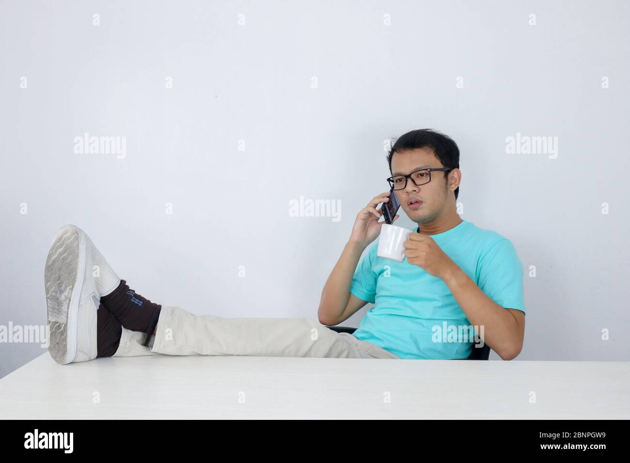 Young asian man shocked when he looking smartphone with leg on the ...