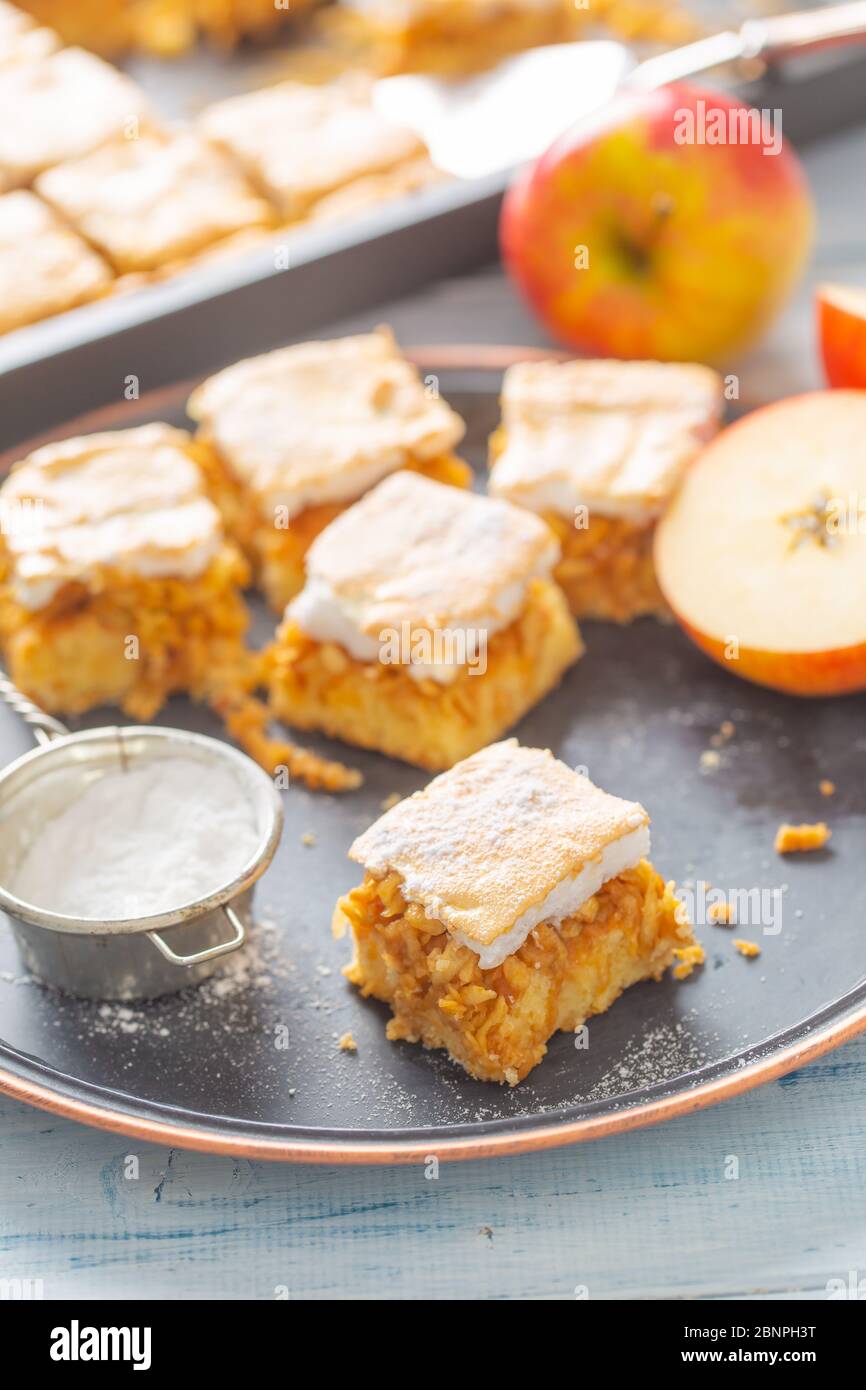 Five cubes of apple plie with a cream topping, sugar sieve and half-cut ...