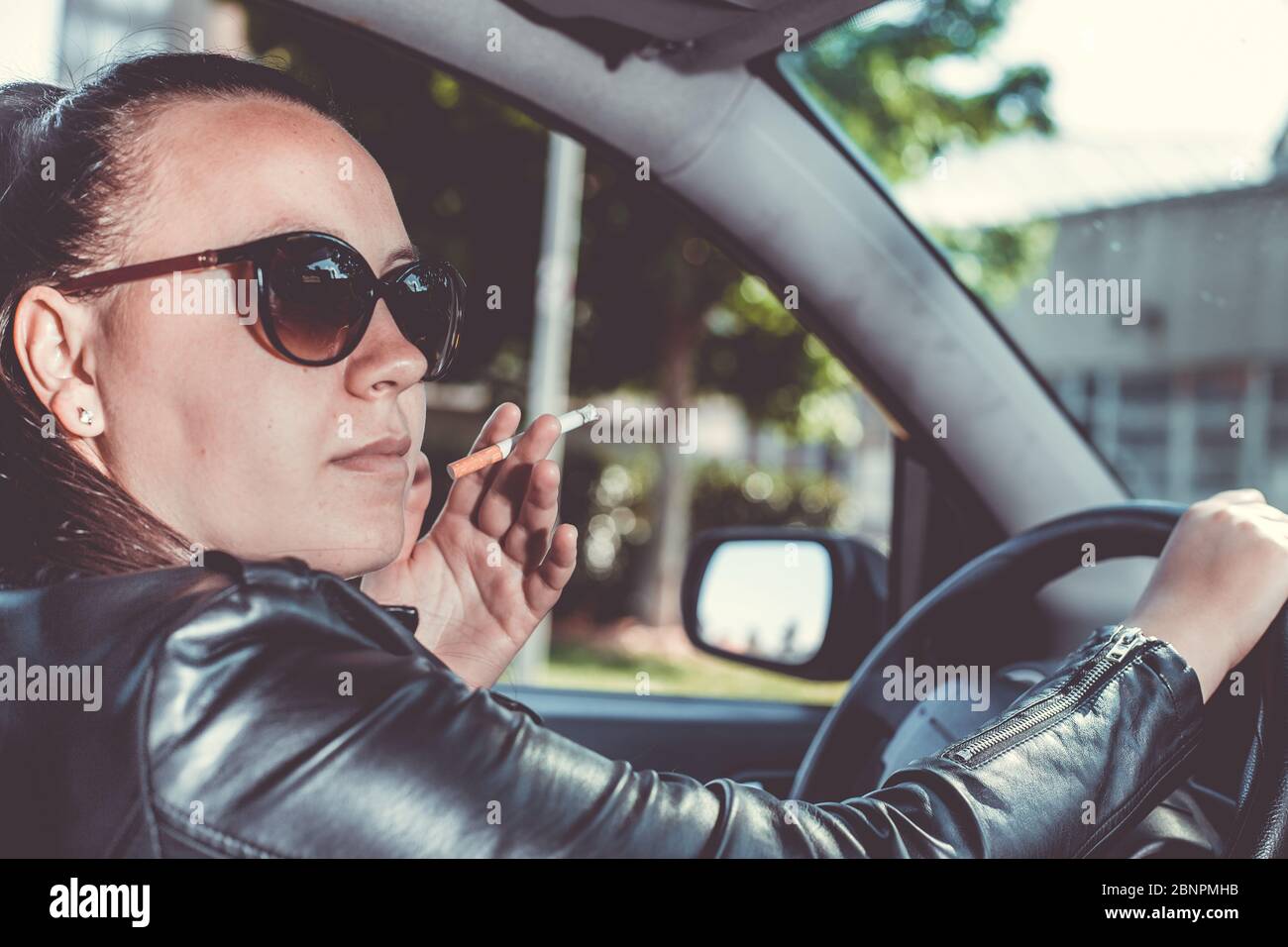 Close up of woman hand smoking cigarette inside the car while driving ...