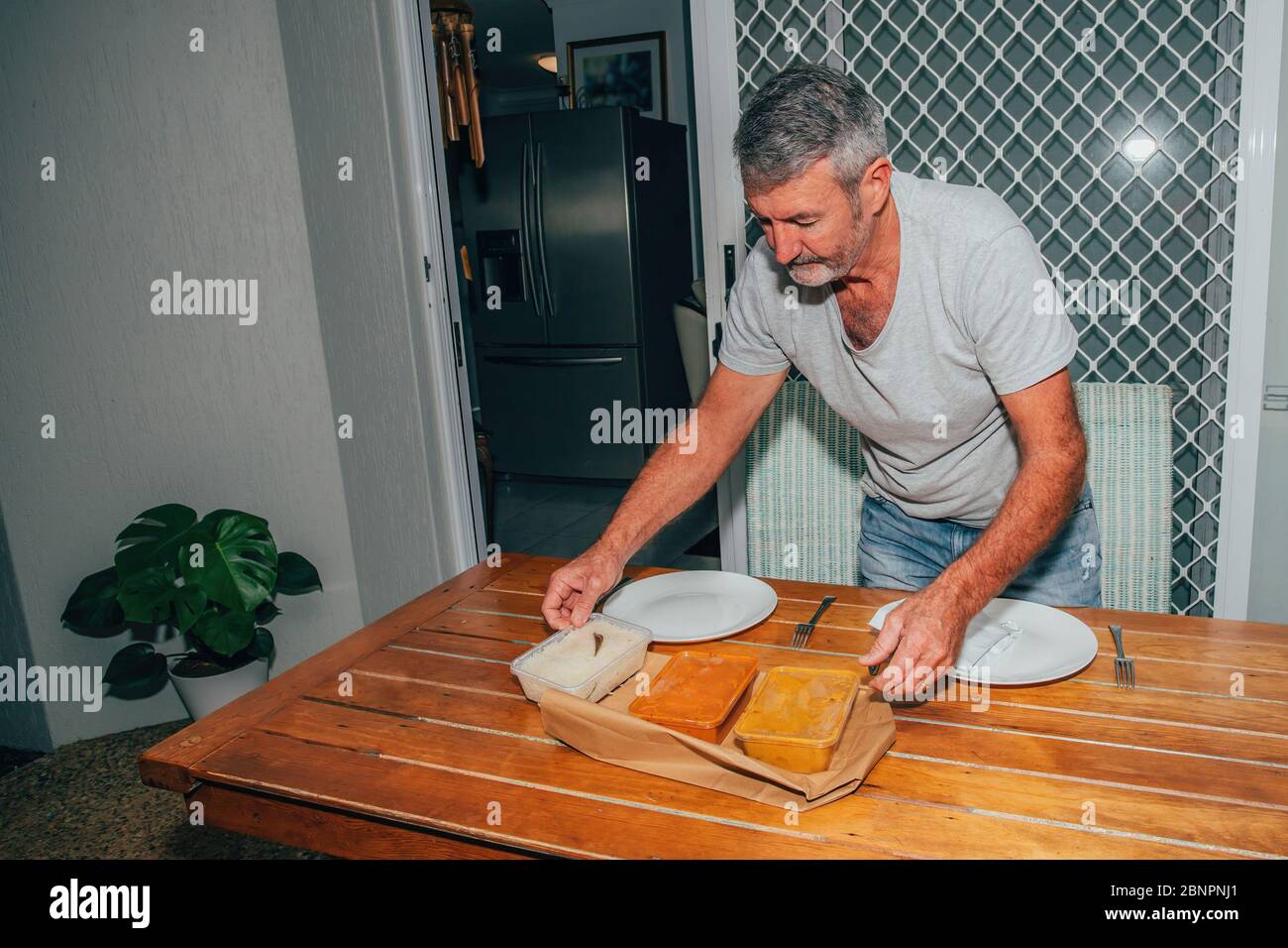 Man serving dinner from the delivered Indian food from a restaurant ...