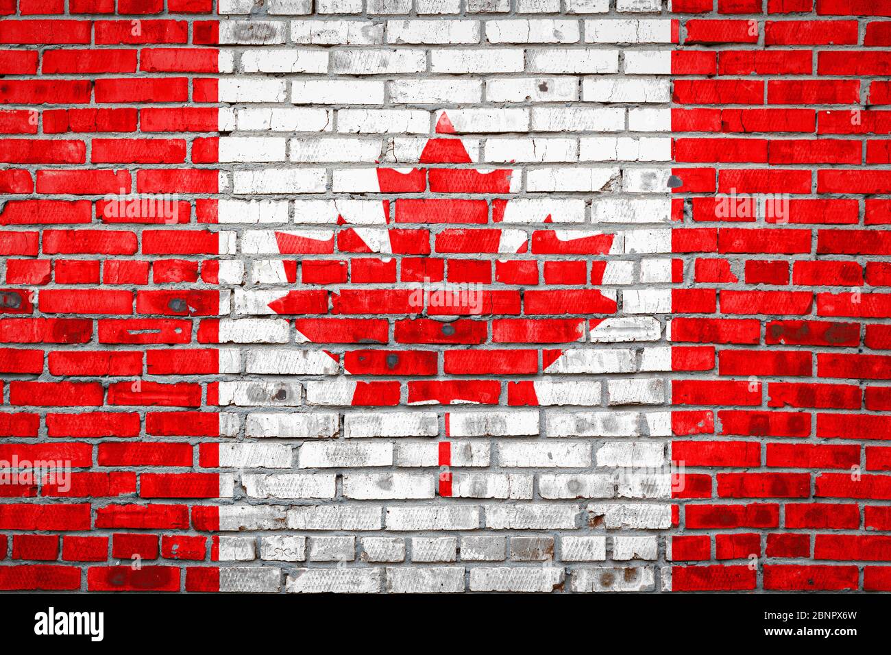 National flag of Canada depicting in paint colors on an old brick wall ...