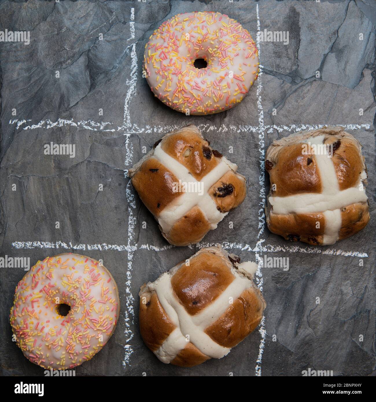 Playing noughts and crosses with donuts and hot cross buns, one of ...