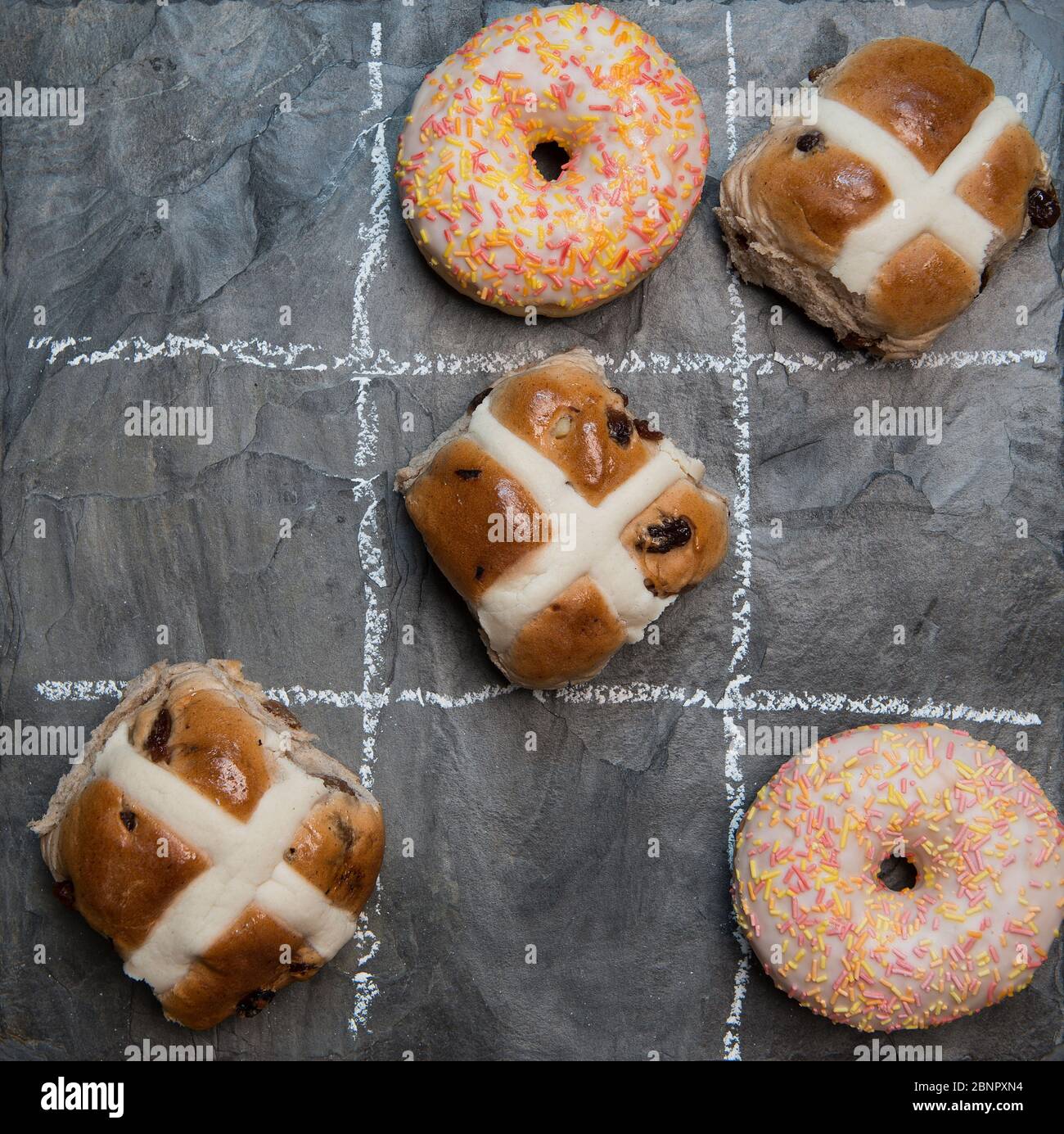 Playing noughts and crosses with donuts and hot cross buns, one of ...