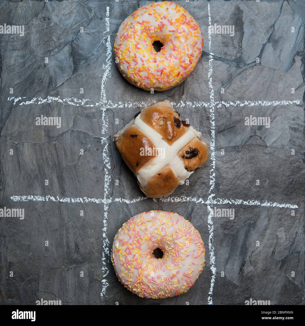 Playing noughts and crosses with donuts and hot cross buns, one of ...