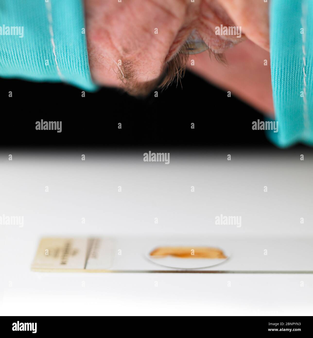 Female scientist in protective clothing examining microscope specimen ...