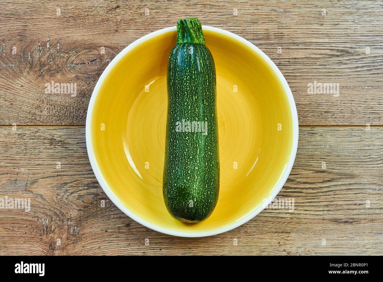 color still life - pale green zucchini squash on a yellow plate on a ...