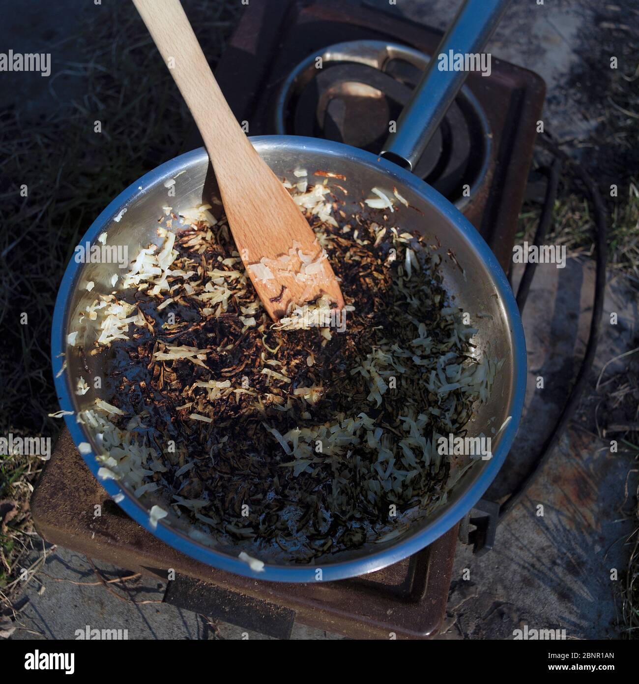 Burnt vegetables on a bottom of the stainless frying pan, overhead shot ...