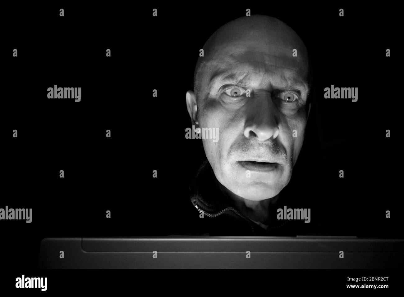 Emotionally disturbed person looking at his laptop, in black and white ...