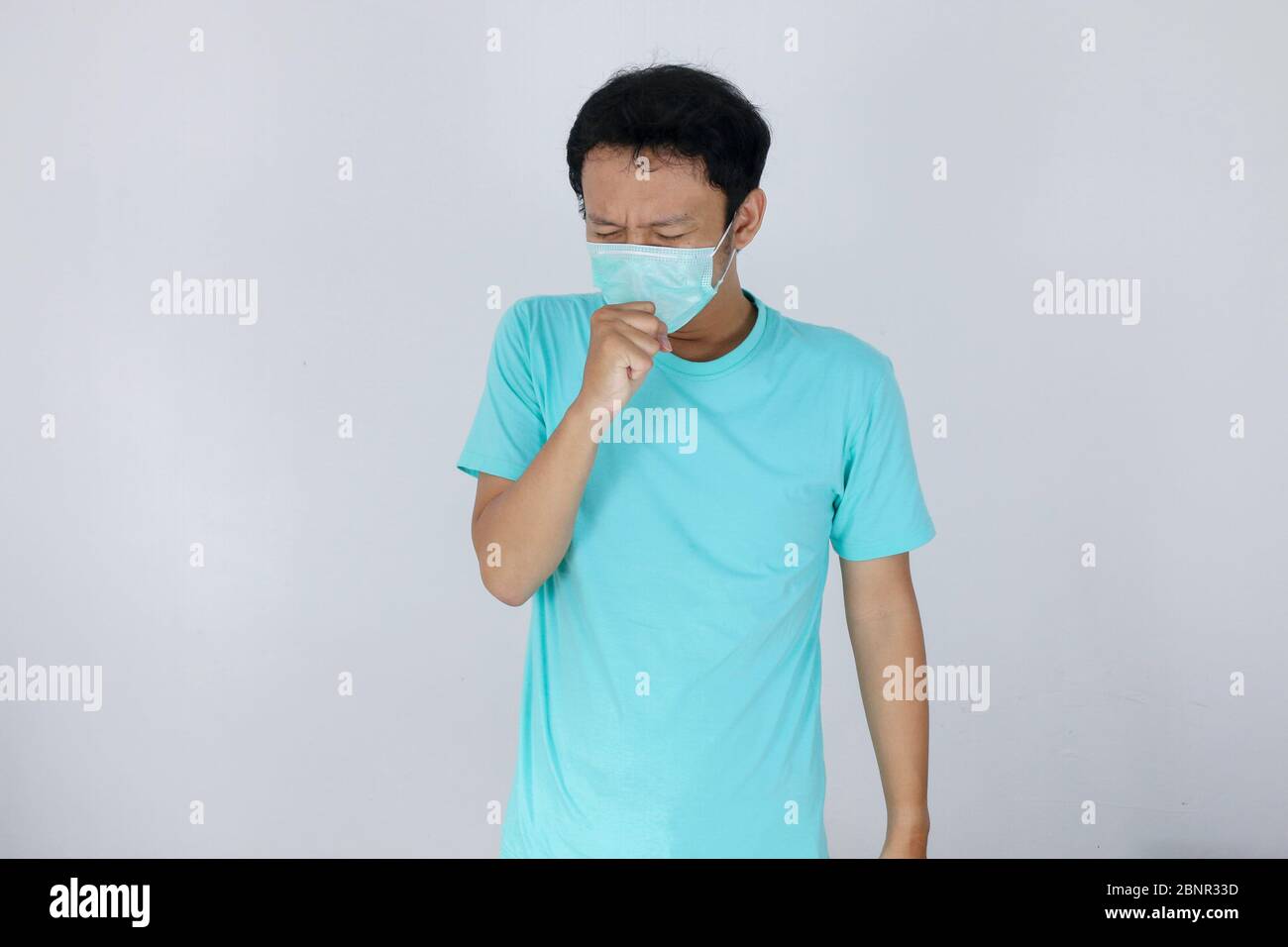 Young asian man wearing medical mask is suffering from severe headache ...