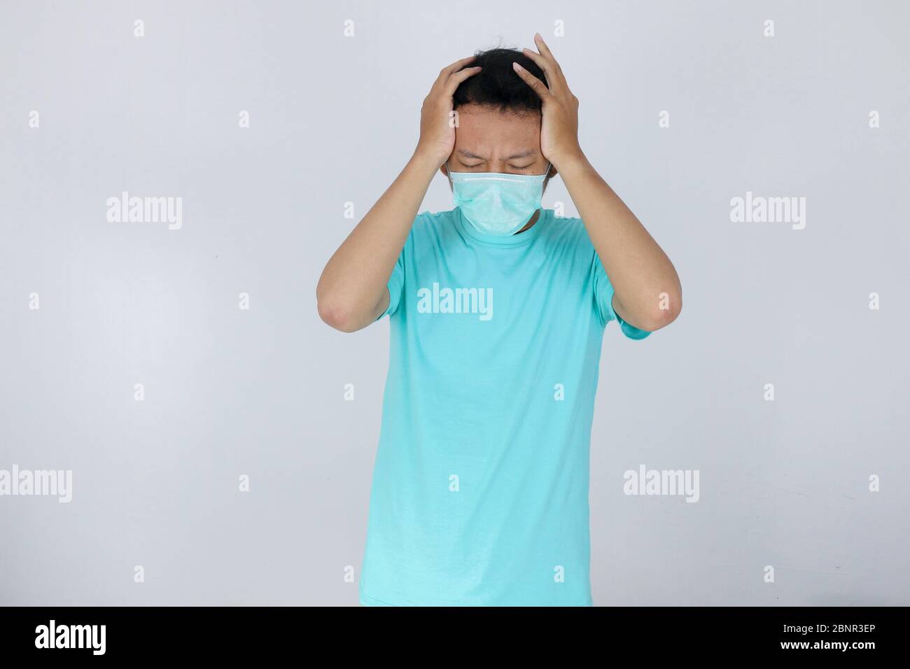 Young asian man wearing medical mask is suffering from severe headache ...