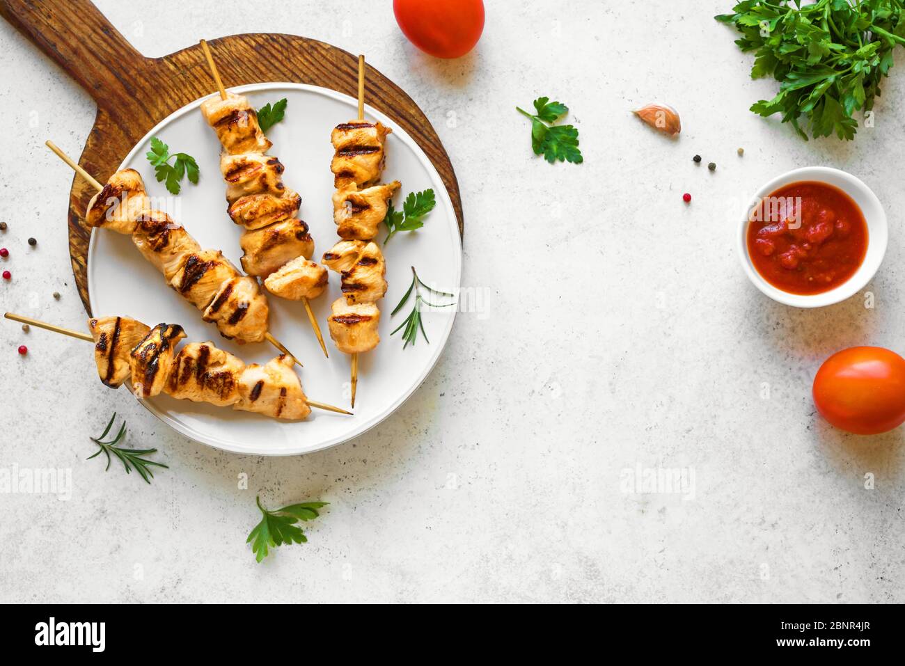 Grilled chicken kebabs on skewers on white background, top view, copy space. Meat pork, chicken ...