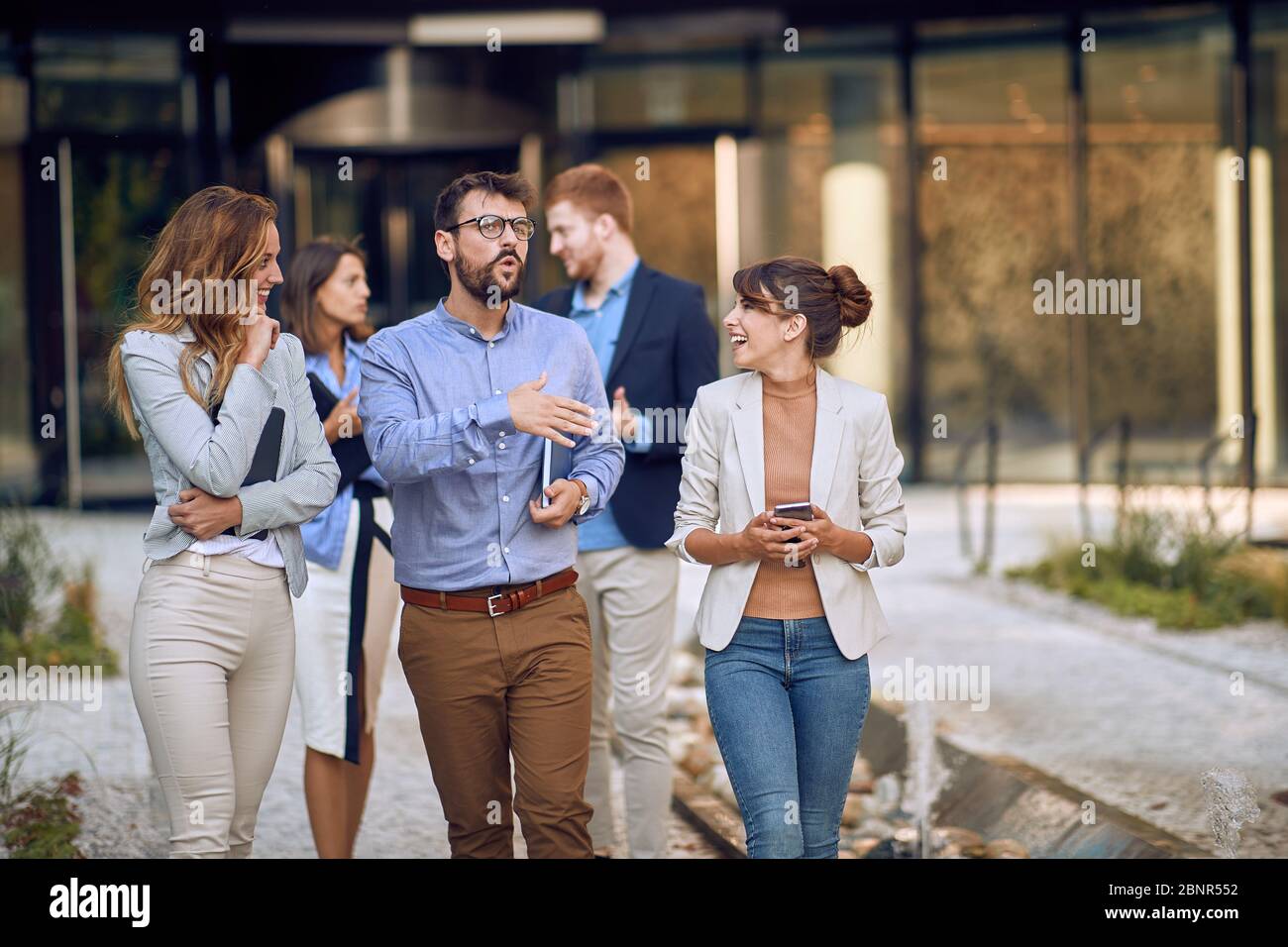 group of young business people in front of a building, carrying tablets ...