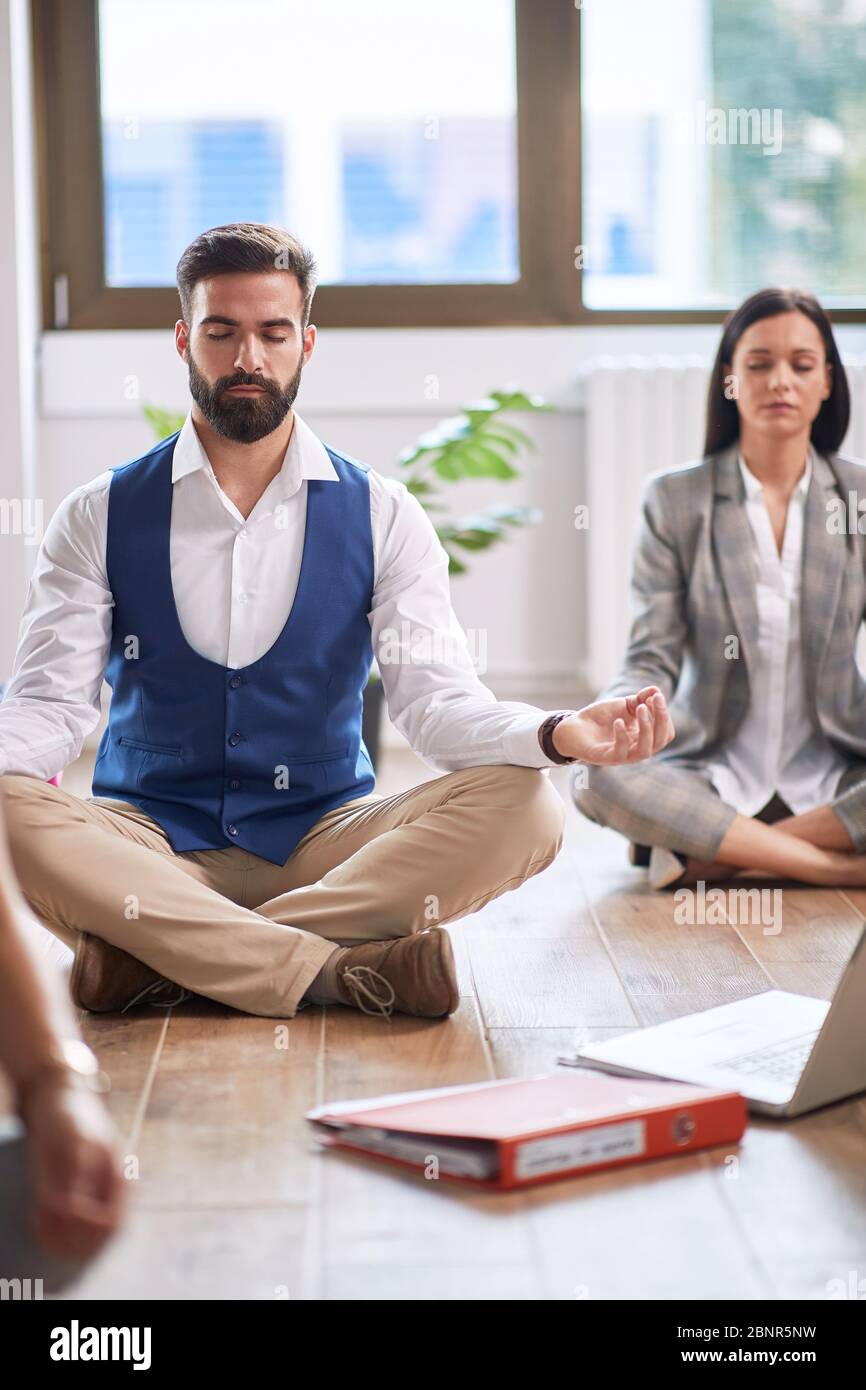Businessman and businesswoman meditating at work. Coworkers sitting on ...