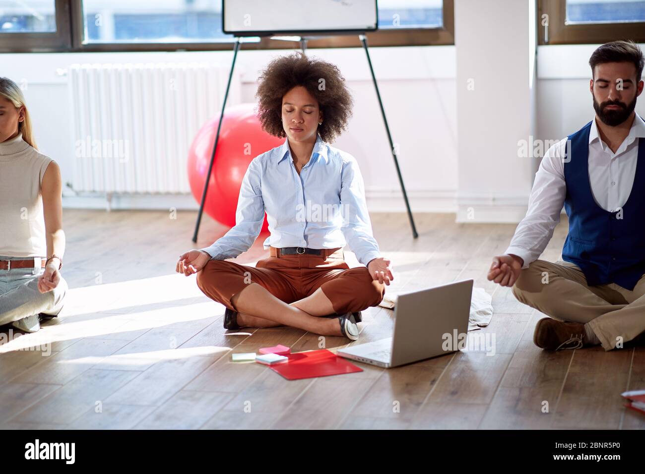 Coworkers practicing meditation at work. Coworkers sitting on the floor ...