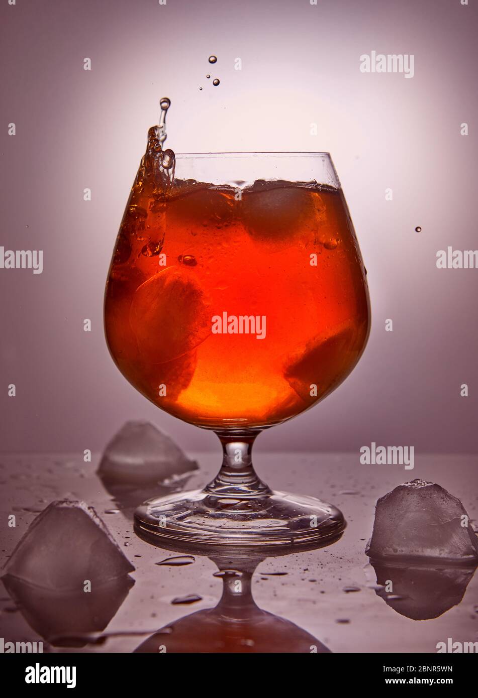 Whiskey, bourbon, brandy or cognac with ice on a pink background ...
