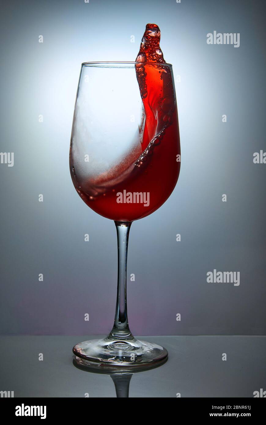 Glass of red wine with wave on blue background. Wine glass and ...
