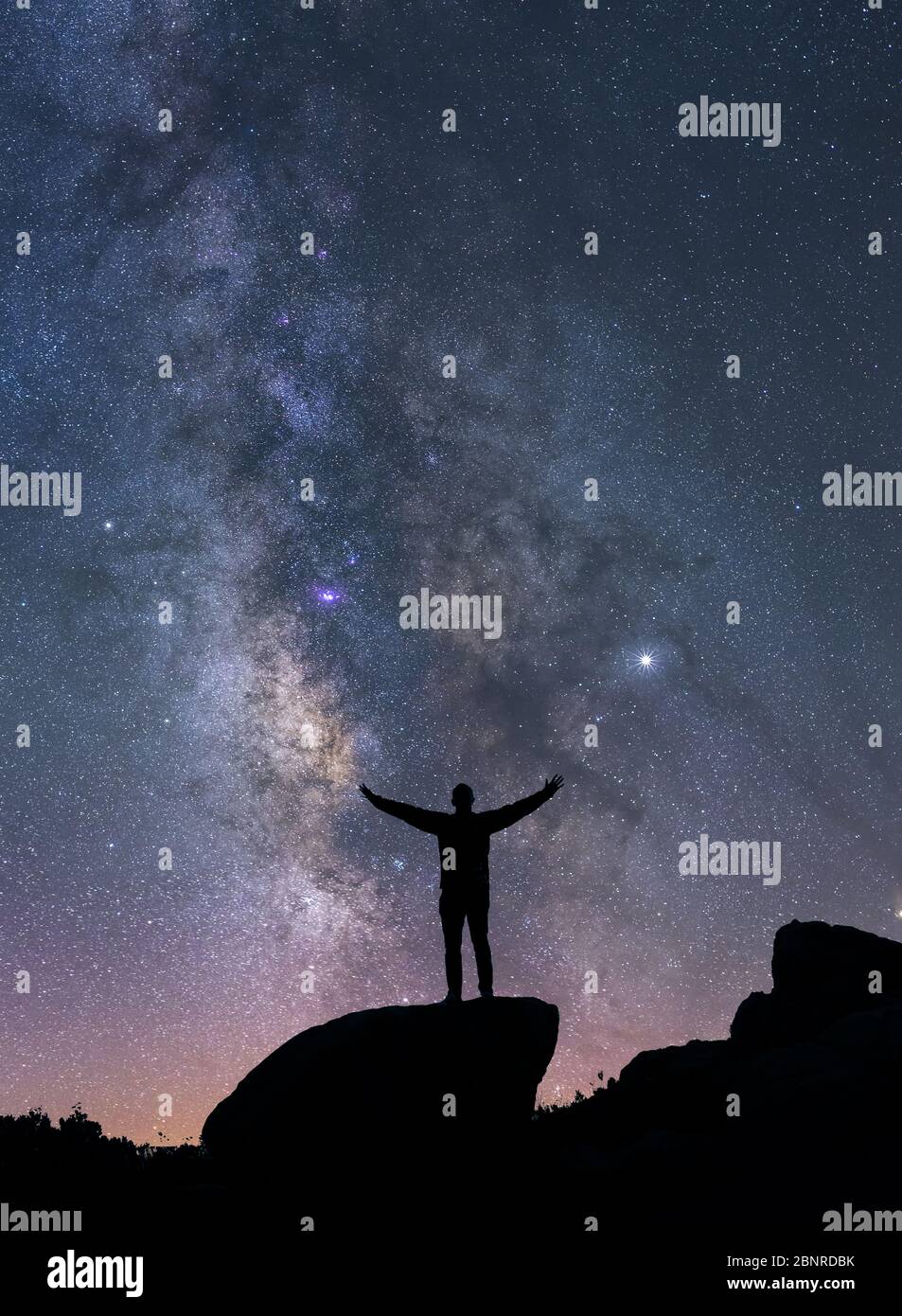 Silhouette of a man with open arms looking at a night sky with the ...