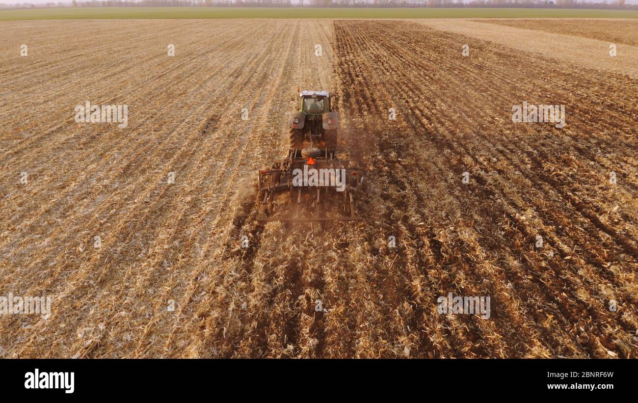 Tractor plowing field after harvesting Stock Photo - Alamy