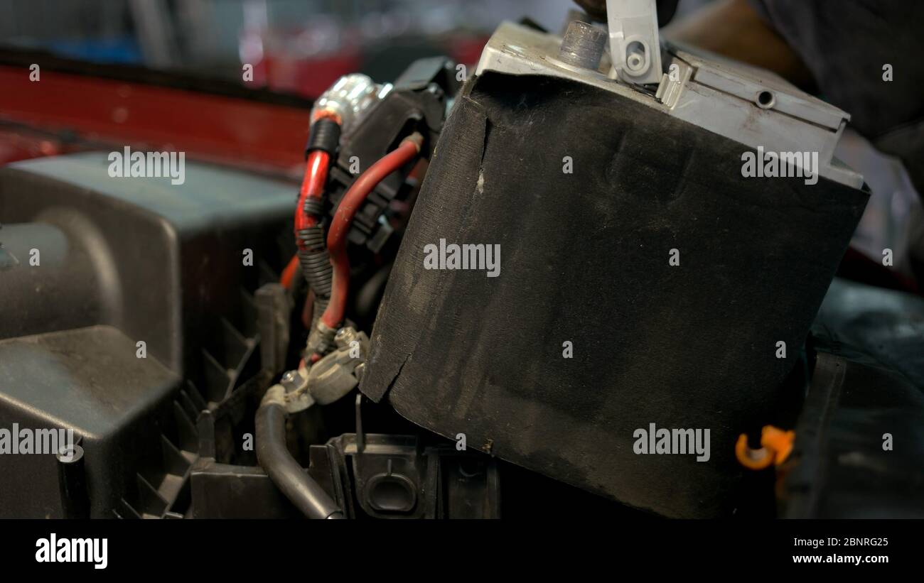 Car service worker installing accumulator into a car engine Stock Photo ...