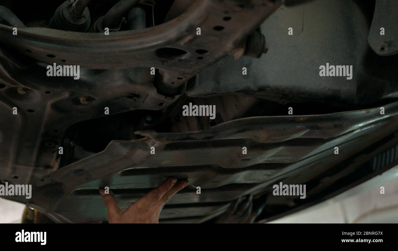 Mechanic screwing car gear bolts in the bottom of the car Stock Photo ...