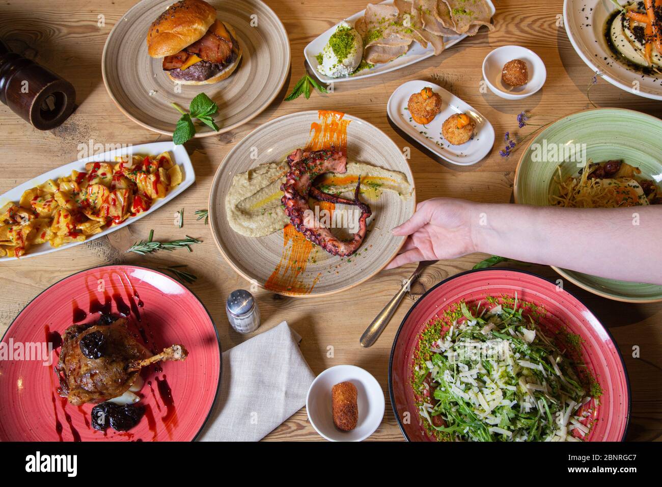 Human hand serving a plate over a variety of meat and fish meals ...