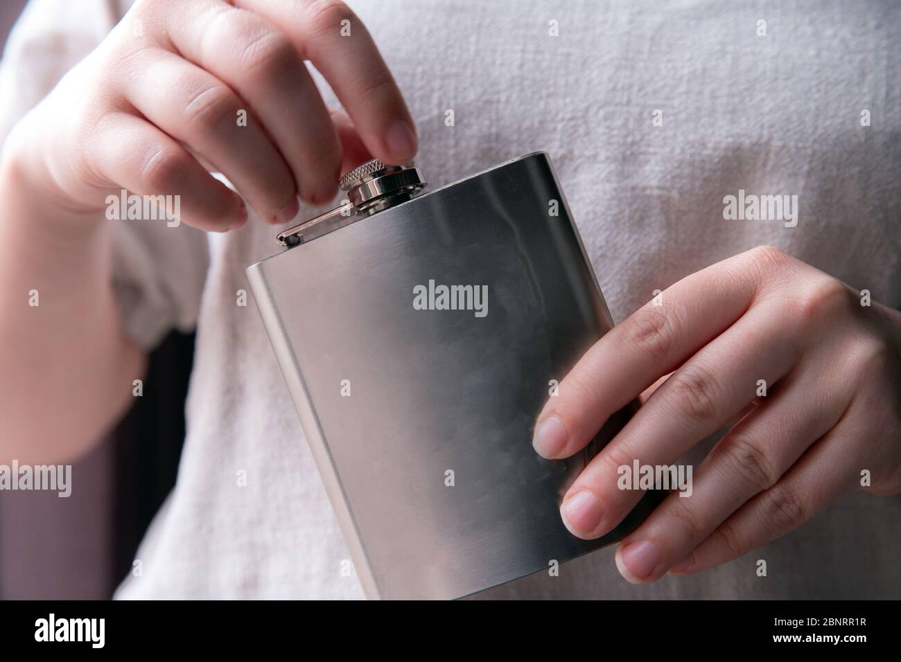 Hand holding a stainless steel hip flask for liquor, alcohol and drink ...