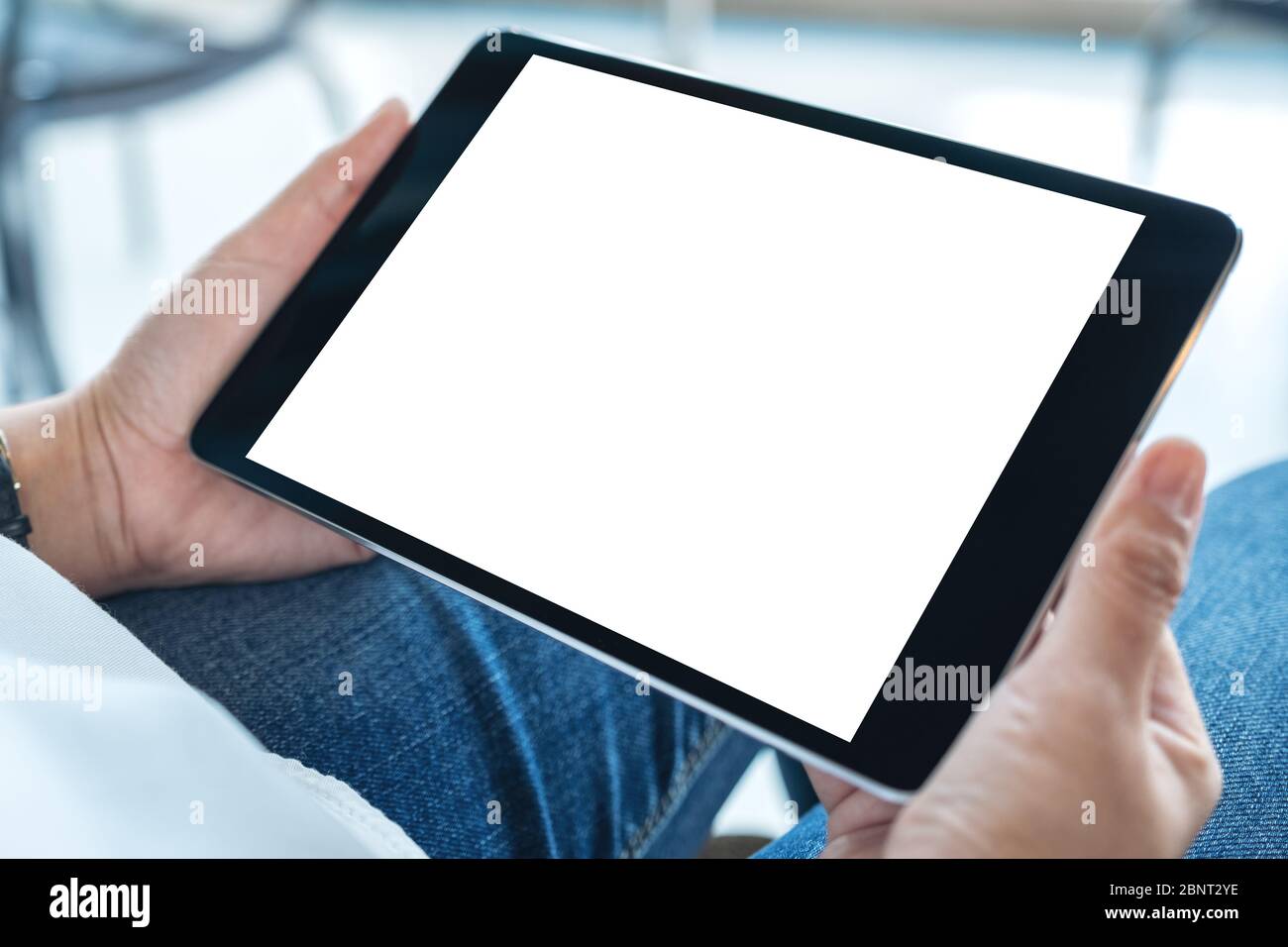 Mockup image of a woman sitting and holding black tablet pc with blank ...