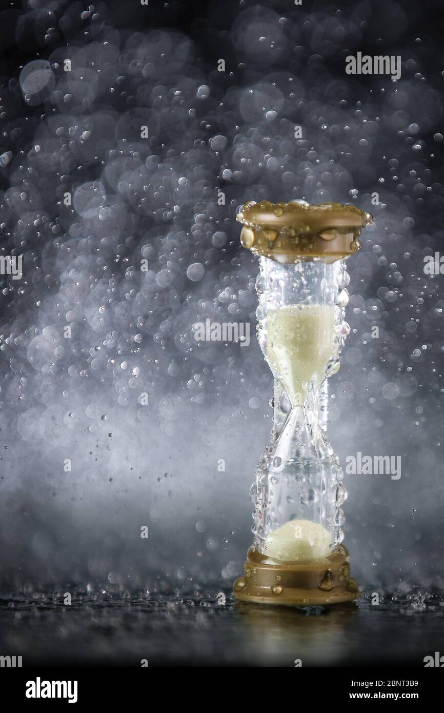 hourglass under the water drops isolated on black background. Time ...
