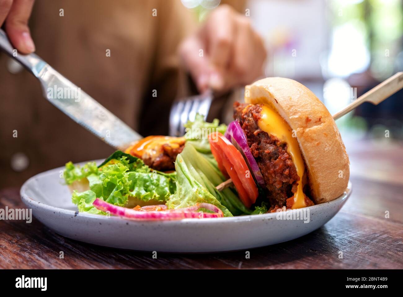 woman eating beef hamburger with knife and fork in the restaurant Stock ...