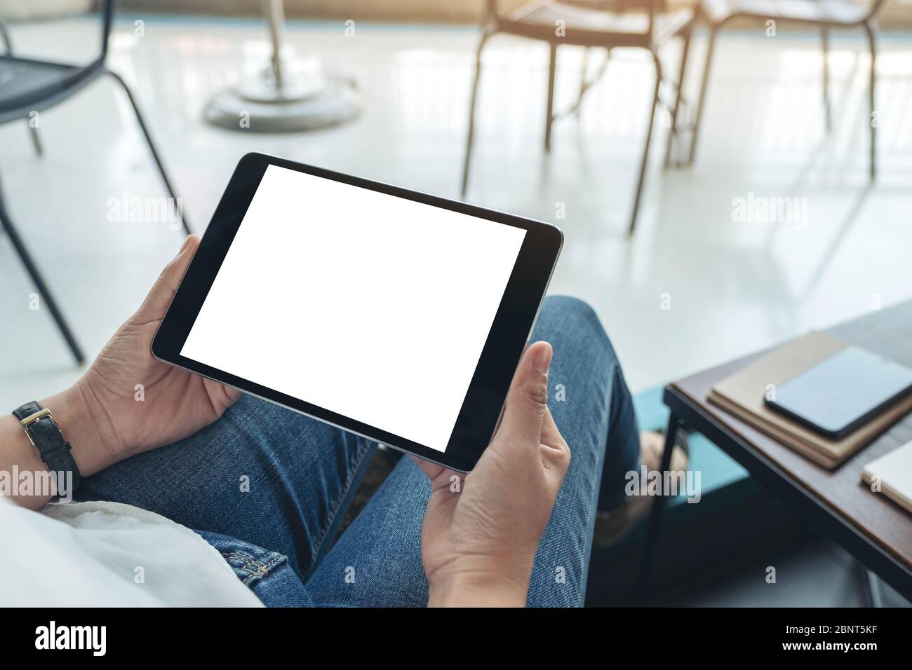 Mockup image of a woman sitting and holding black tablet pc with blank ...