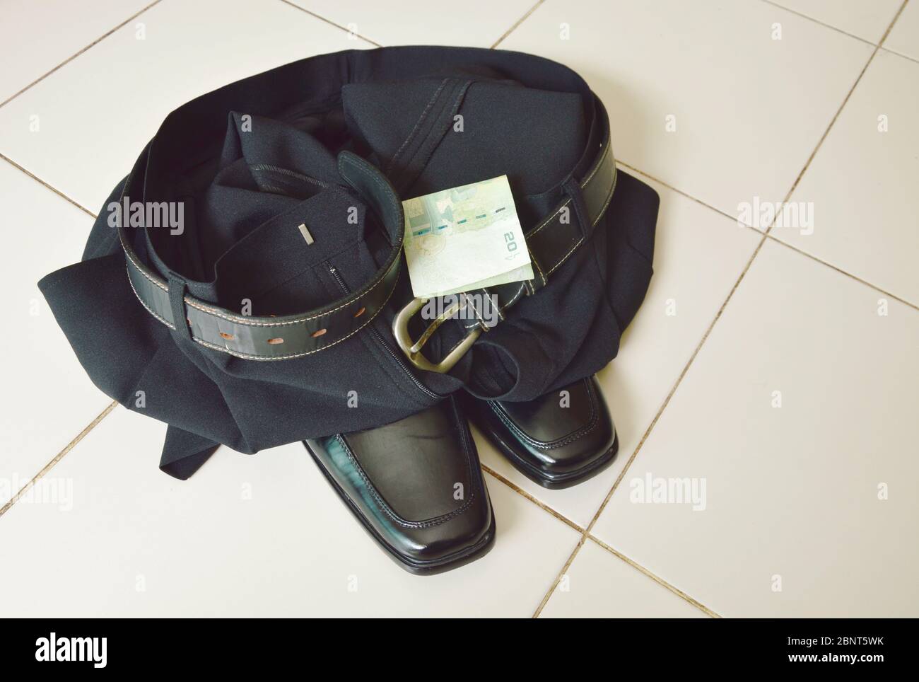 Banknote with black business pant and lather shoe on white tile floor ...