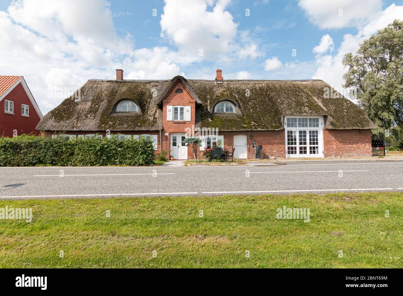Typical farm house with thatched roof in summertime of a Danish village ...