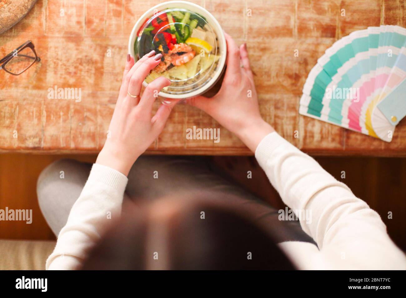 Overhead anonymous woman eating healthy dish for lunch over table ...