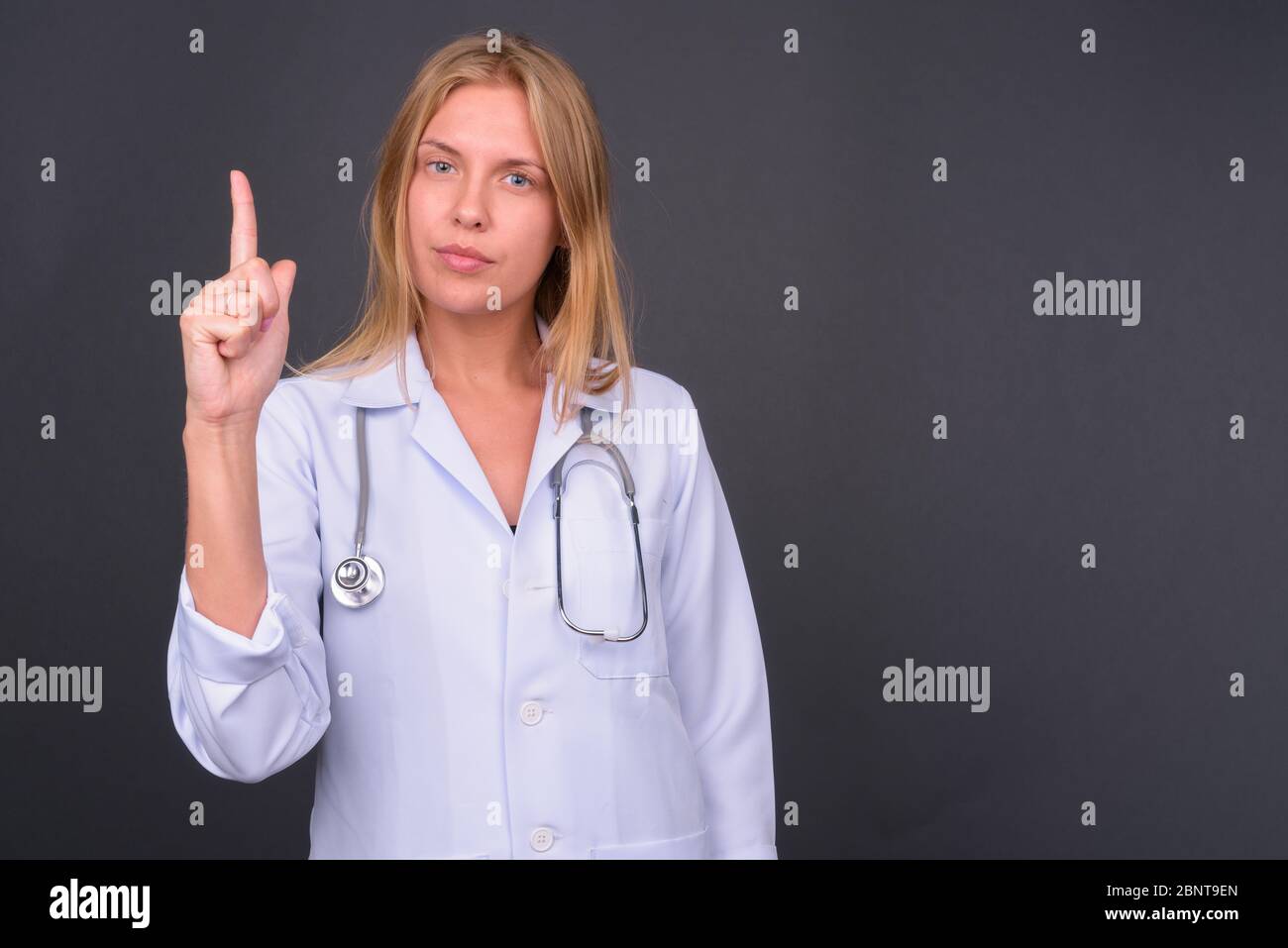 Beautiful young woman doctor pointing up. Isolated on white Stock Photo ...