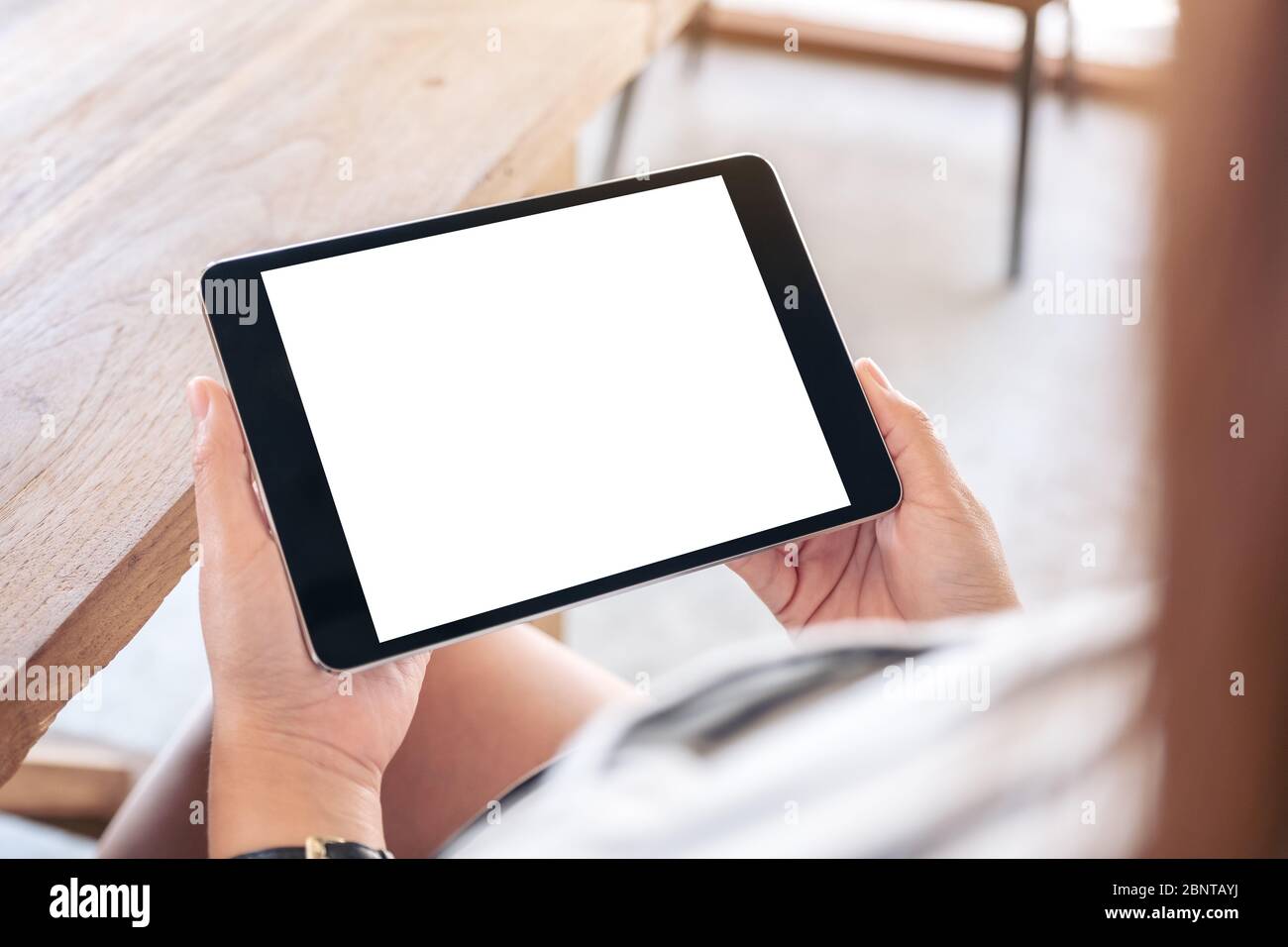 Mockup image of a woman sitting and holding black tablet pc with blank ...