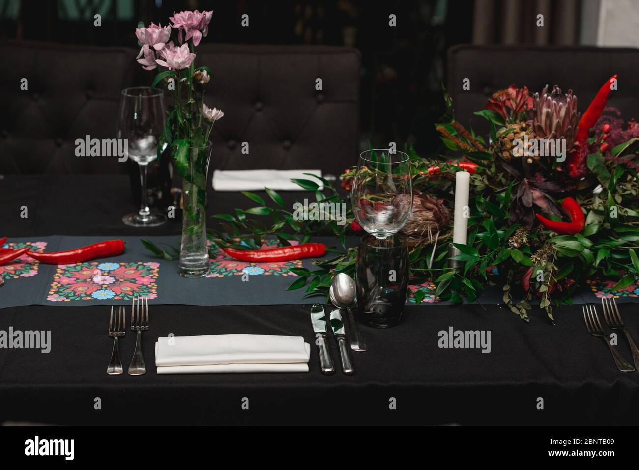 Served restaurant table. Red pepper decoration on a black tablecloth ...